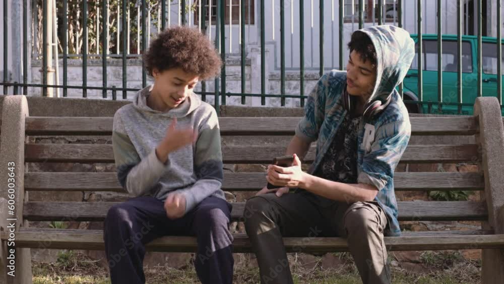 Two mixed race african teen boys sitting on park bench. The older boy ...