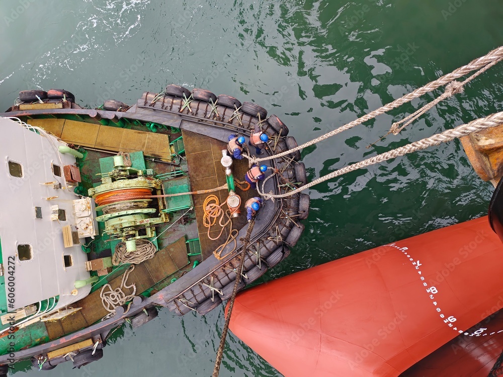 Tug or mooring boat crews are pulling ship's mooring ropes during ...