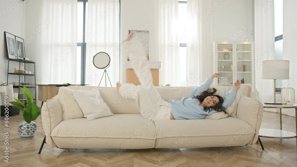 Latino girl laughing, enjoying rest on cozy sofa, feeling overjoyed ...