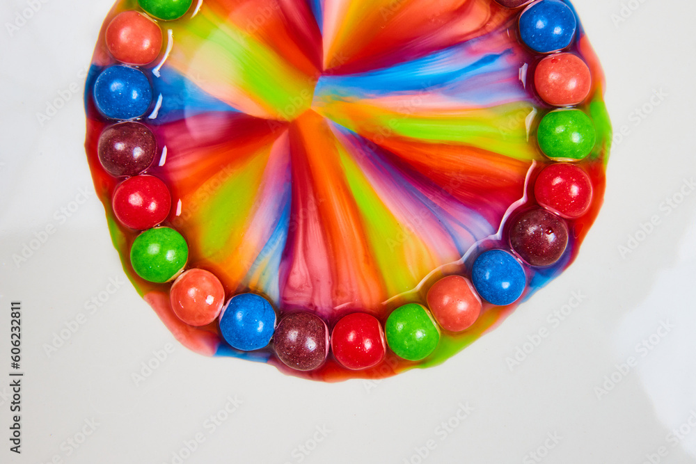 Rainbow of colors from skittles candy mixing with water and spreading ...