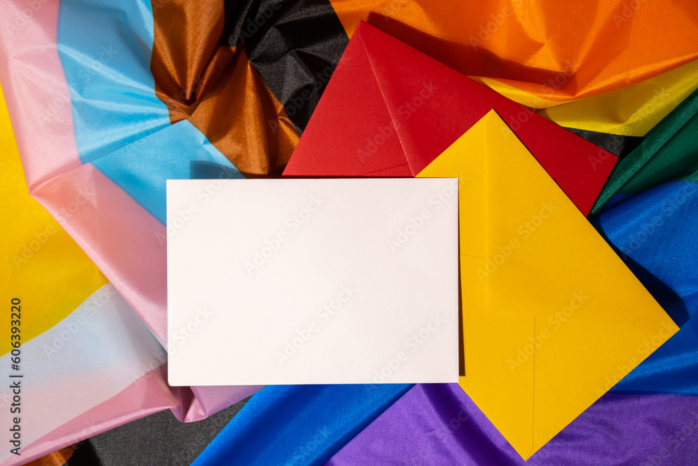 Empty paper blank on Rainbow LGBTQIA flag made from silk material. Mock ...