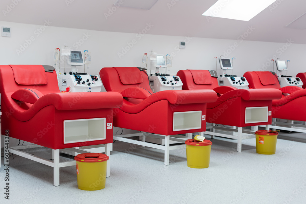 row of modern and comfortable medical chairs near transfusion machines ...