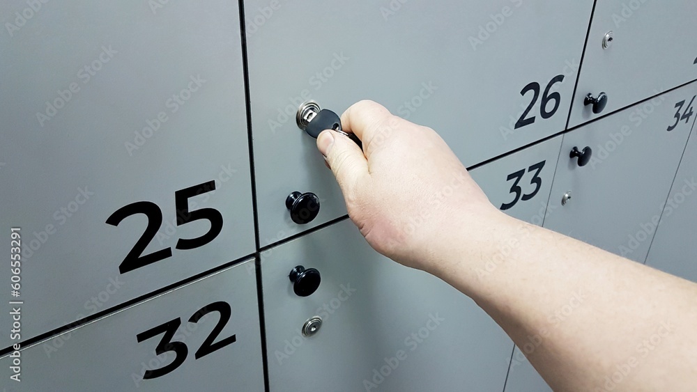 A man's hand opens the door of a locker for storing personal items in a ...