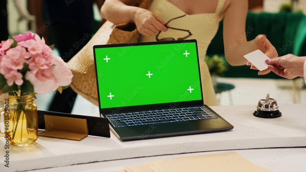 Laptop with greenscreen template on hotel reception counter next to ...