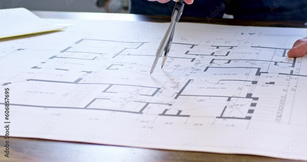 Engineer draws circle using dividers on latest floor plan of building ...
