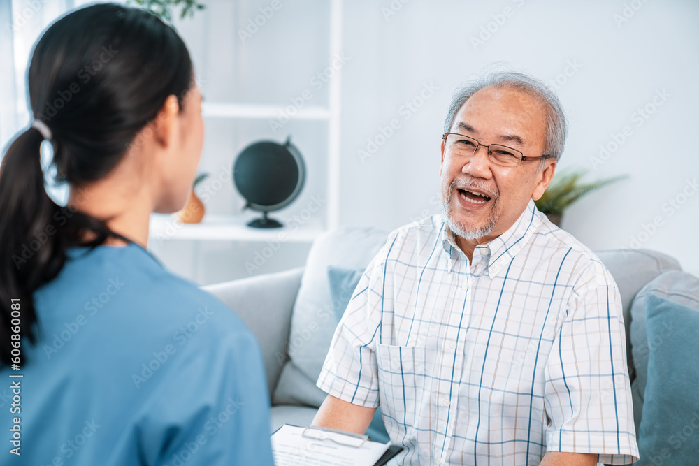 Caring young female doctor examining her contented senior patient with ...