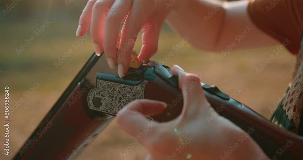 woman with white painted fingernails loads bullet into automatic ...