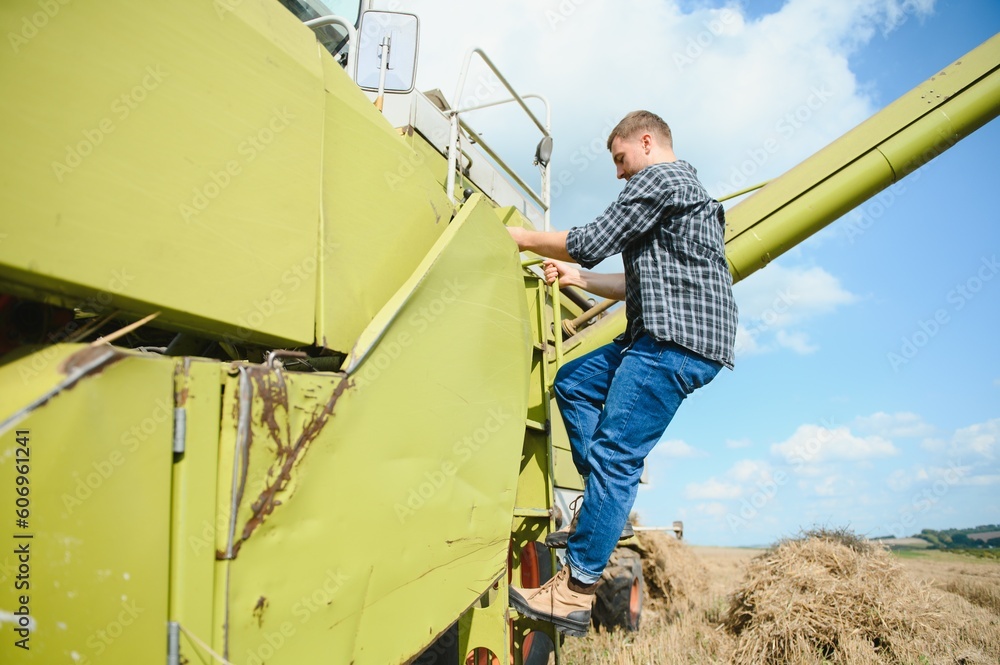 Harvester machine driver climbing into a cab to harvest his wheat field ...