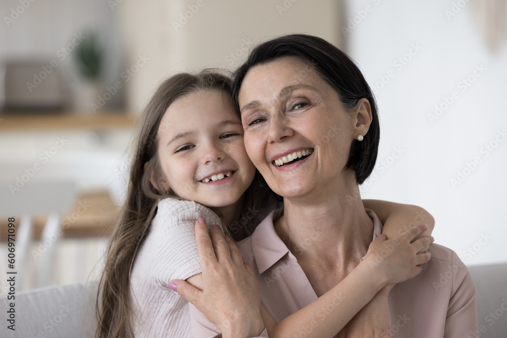 Cheerful pretty cute little grandkid girl hugging happy loving grandma ...