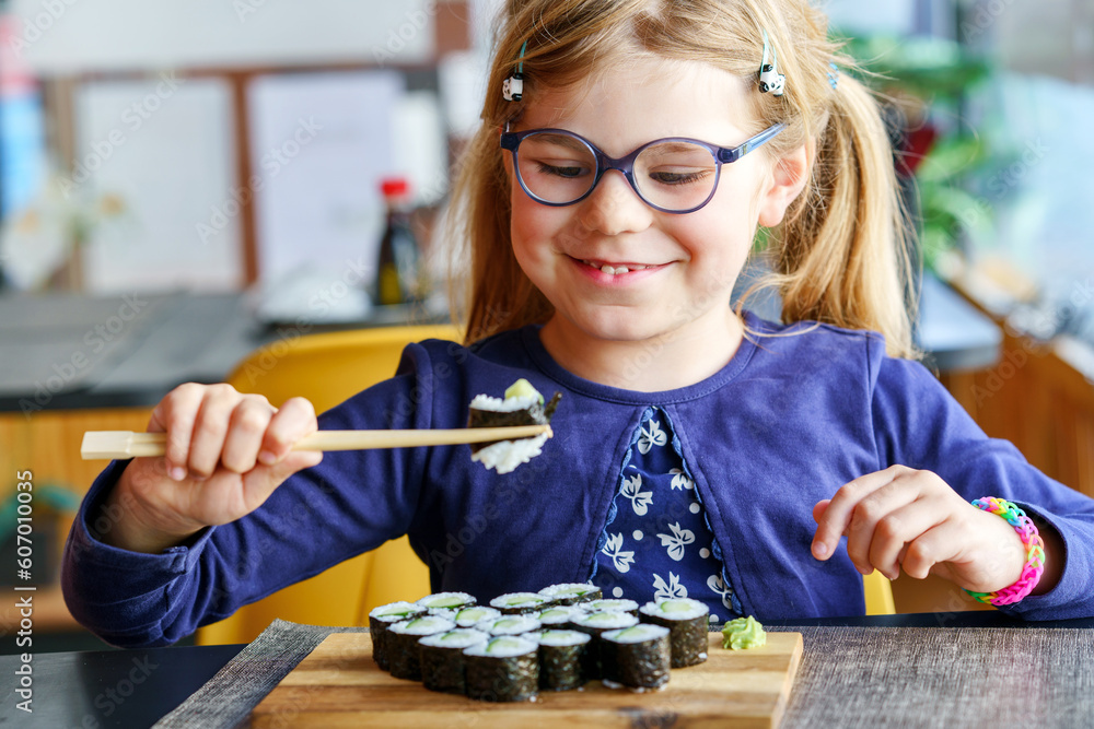 Happy preschool girl eating sushi rolls in a cafe or restaurant using ...