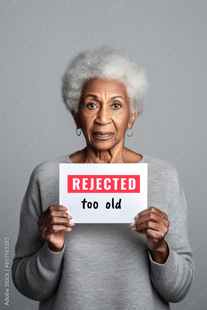 An older African woman holding a paper with words Rejected, Too Old ...
