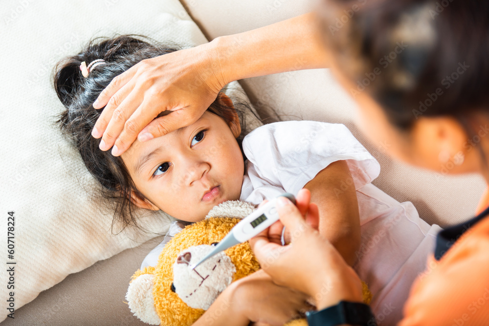 Sick kid. Mother checking temperature of her sick daughter with thermometer in mouth, child ...