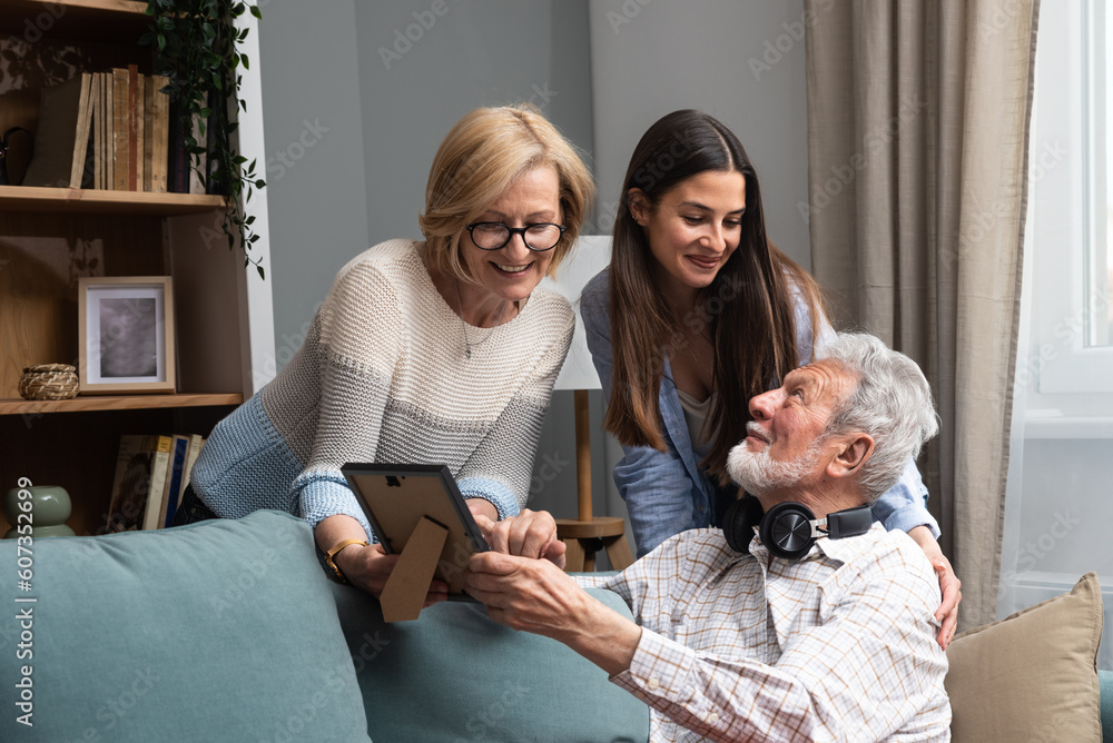 Happy three-generation family hugging sit indoors enjoy time together ...