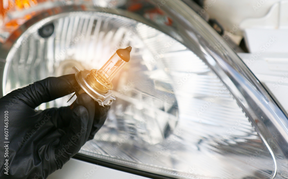 Car mechanic replace the damaged car light bulb and insert the new one ...