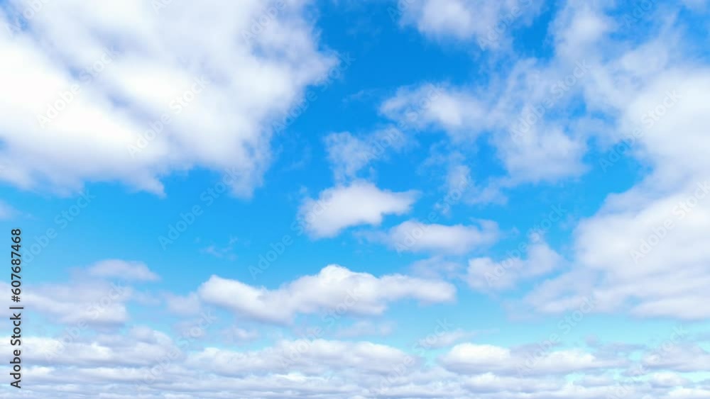 White clouds swiftly traverse the expanse of the blue sky, creating a ...