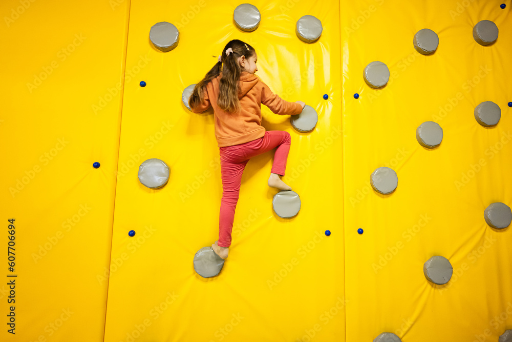 Little girl kid climbing wall at yellow playground park. Child in ...