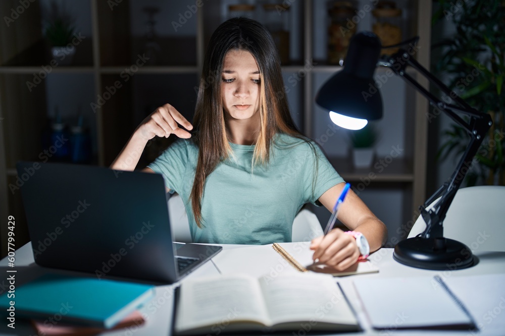 Teenager girl doing homework at home late at night pointing down ...