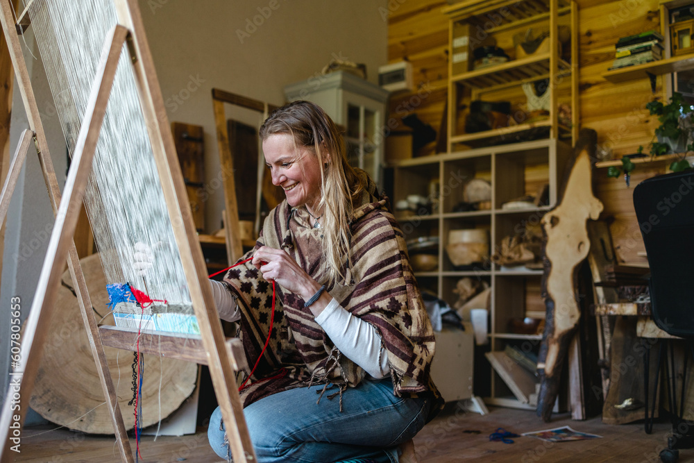 Crafty woman weaving at a loom at her workshop Stock Photo | Adobe Stock