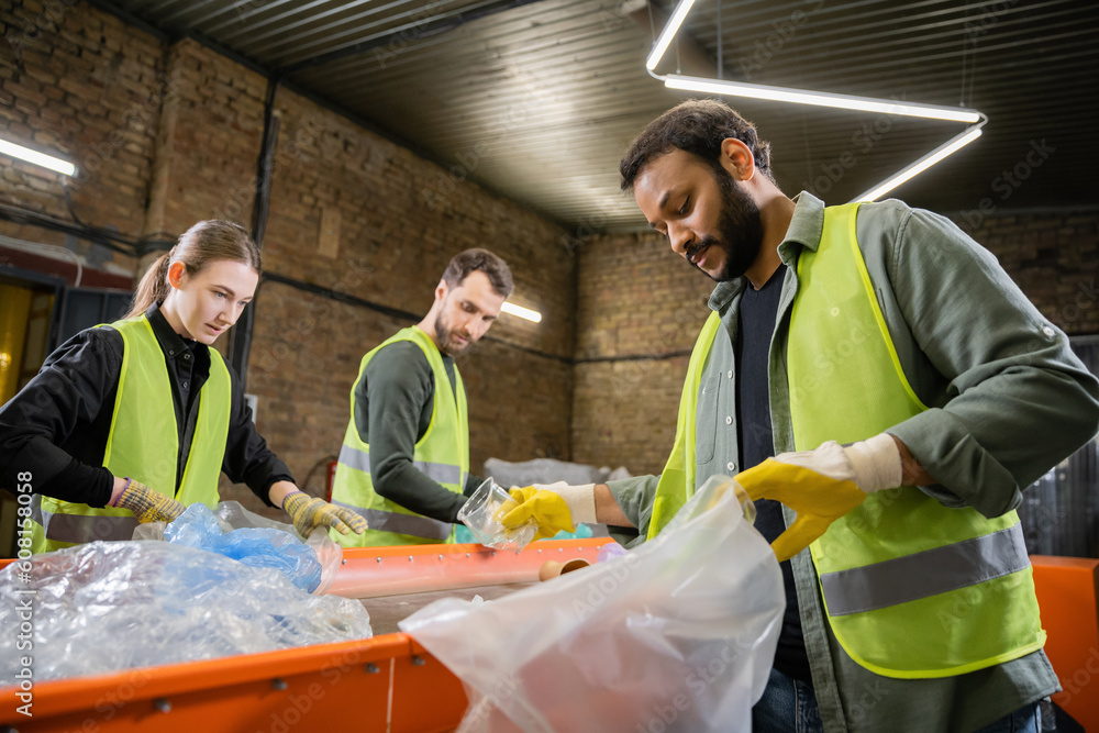 Indian worker in protective vest and gloves putting plastic trash in ...
