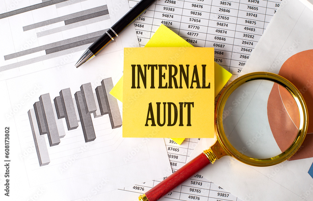 INTERNAL AUDIT text on a sticky on the graph background with pen and ...