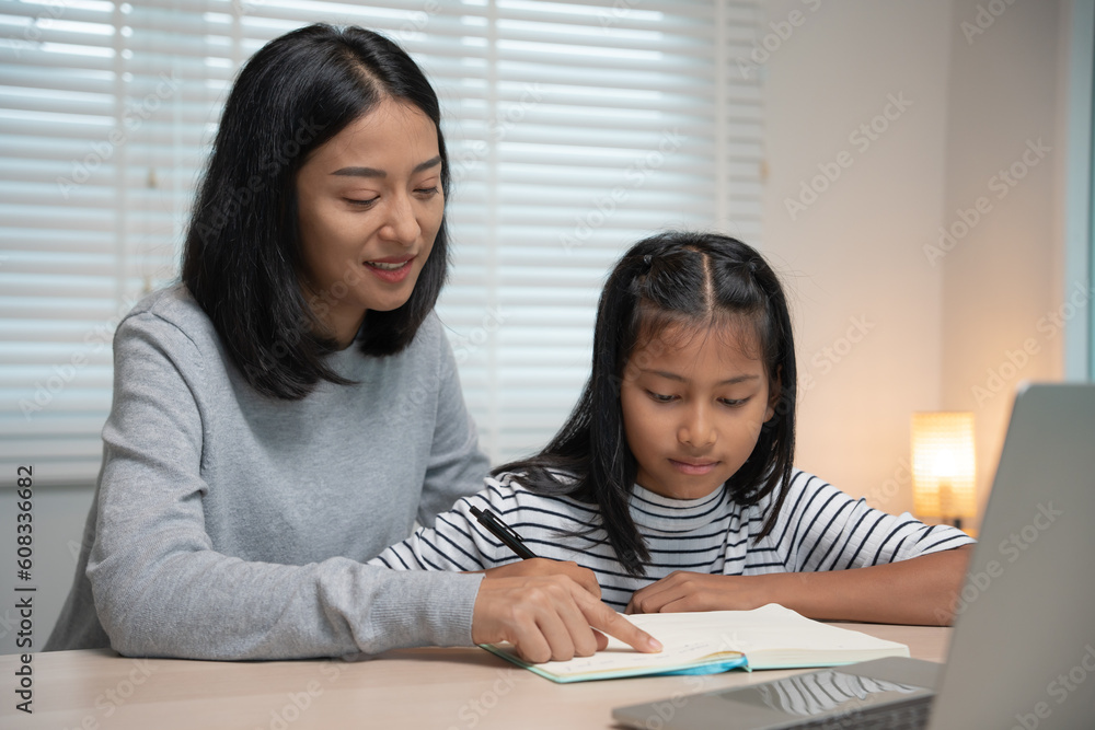 Mother teaching lesson for daughter by laptop. Asian young little girl learn at home. Do ...