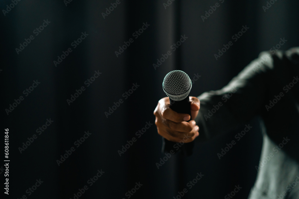 Confident successful speaker man talking on stage with spotlight strike ...