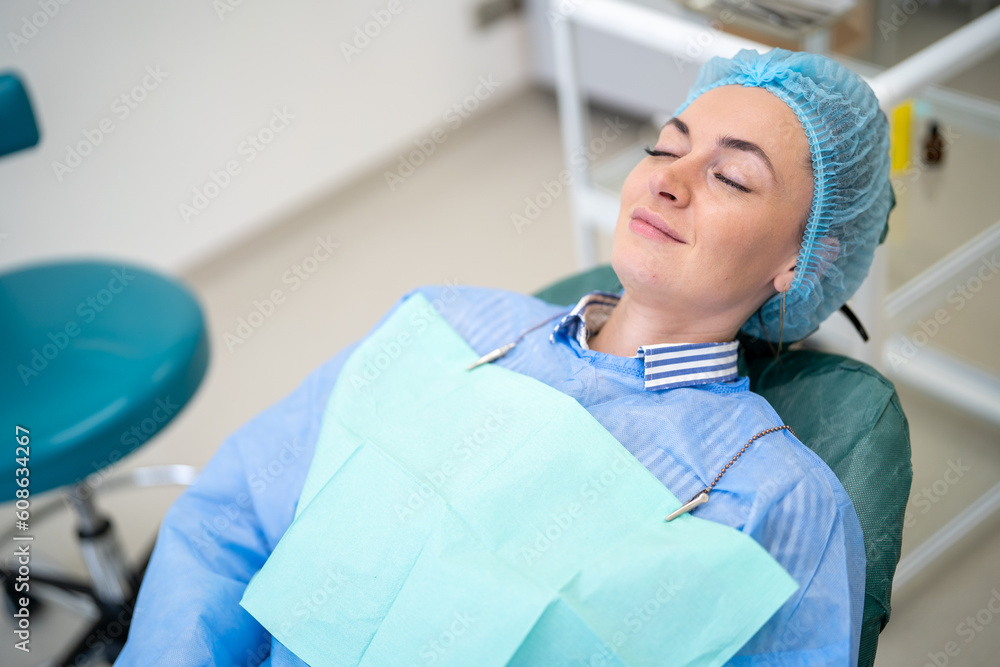 Foto de Gently smiling female dental patient sitting in stomatological ...