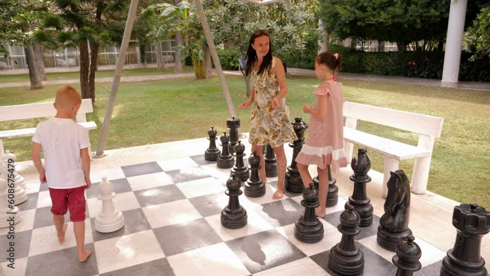 A big cheerful family with bare feet playing chess in the summer in the ...
