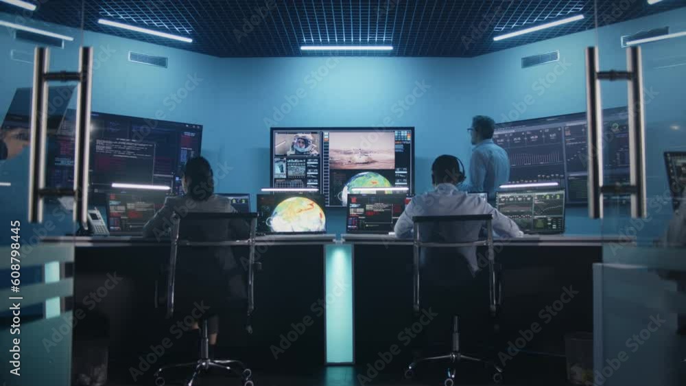Group of employees watch successful spacecraft lift off on big screens ...