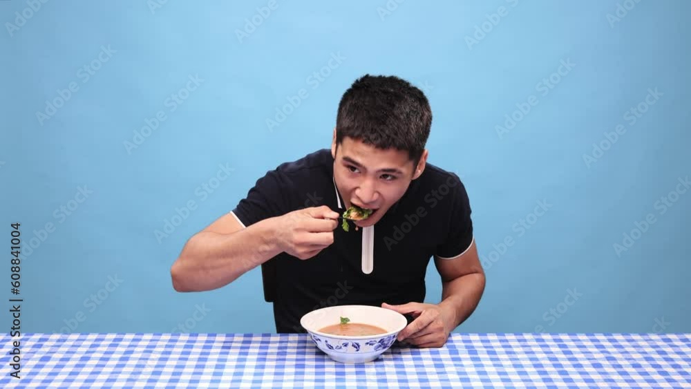 Handsome young man with grimacing face eating spicy soup with noodles s ...