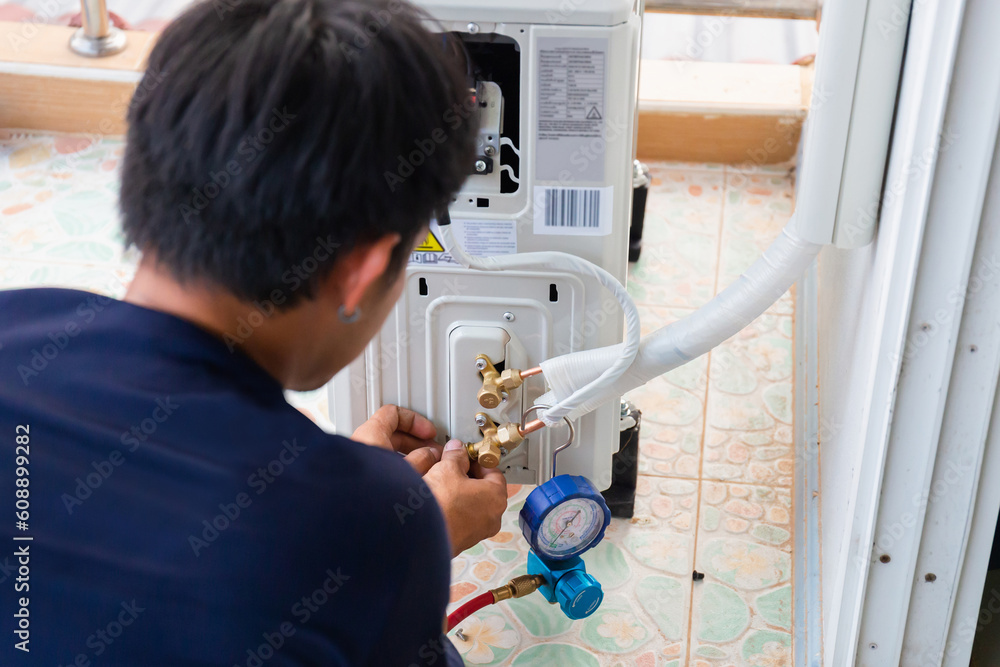 Air conditioning technicians install new air conditioners in homes ...