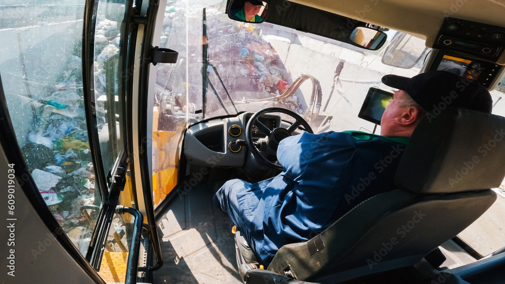 Inside cab view of a man driving heavy machine vehicle, a front loader ...