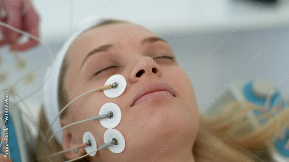 Close-up hands of unrecognizable cosmetologist applying electrodes of ...