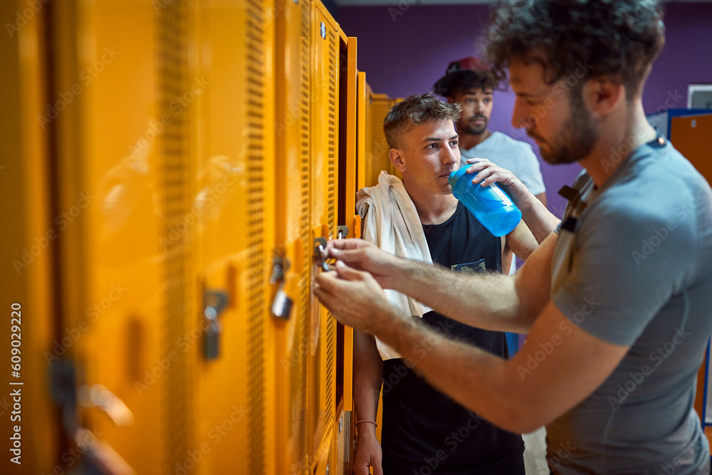 Young men in the gym locker room preparing for workout, getting dressed ...