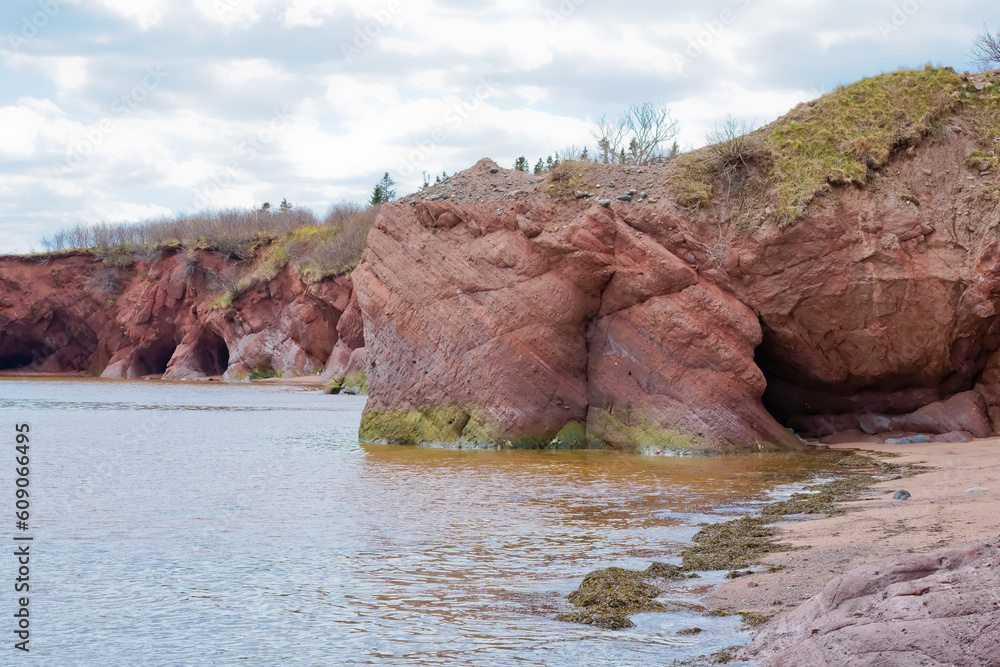 Red stone cliff and sea caves on Gardner creek beach Fundy bay New ...