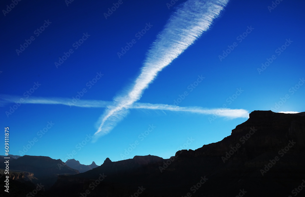 Jet streams in evening sky above the grand canyon, with canyon walls in ...