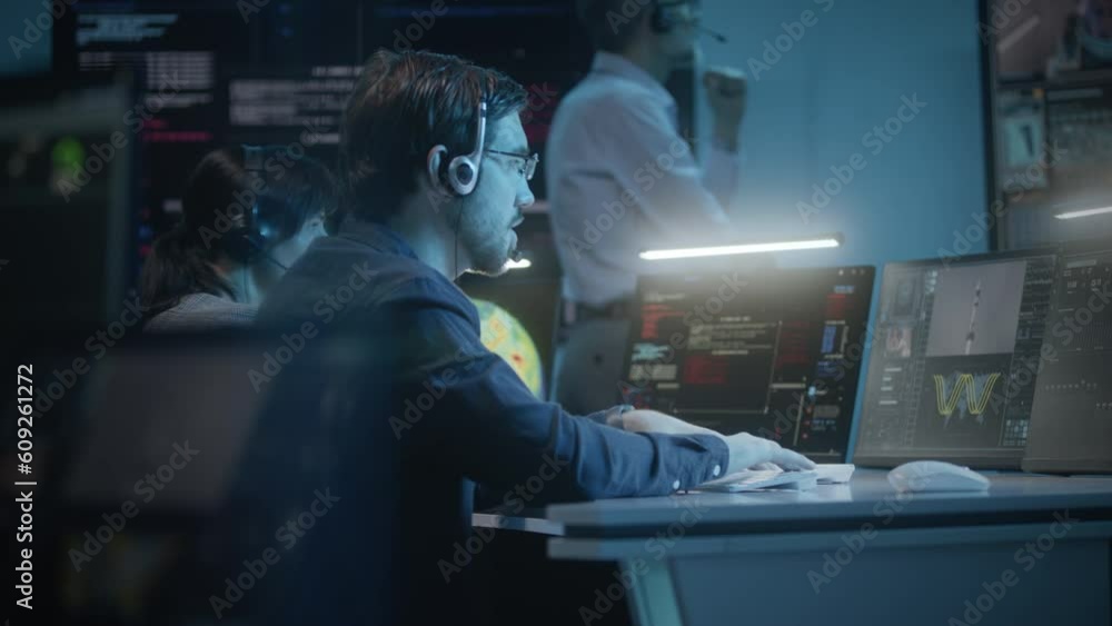 Diverse flight control operators in headsets monitor space mission on ...