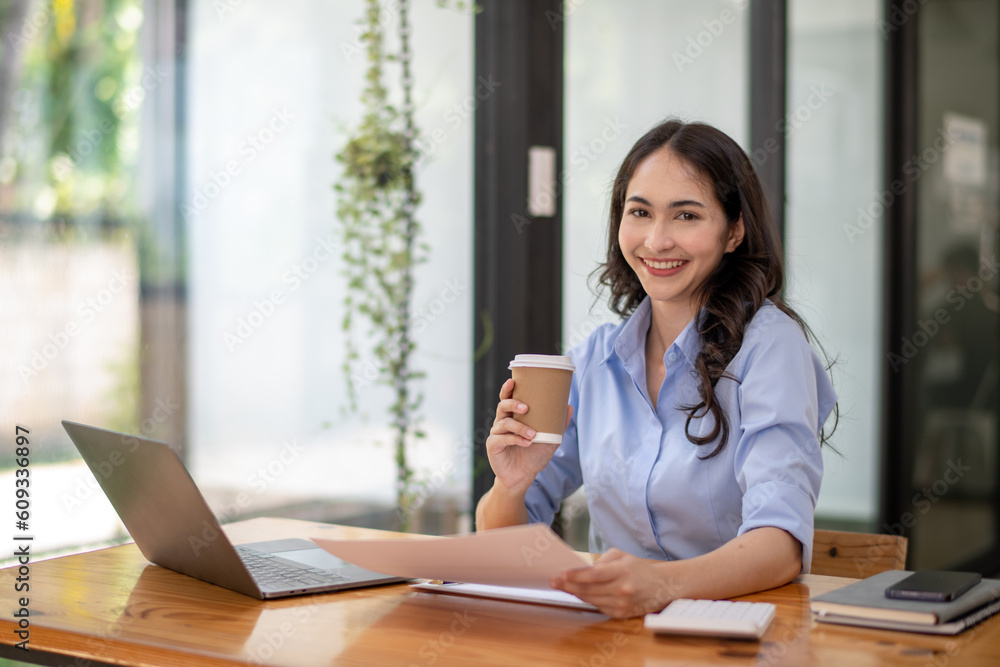 Business woman work happily with warm coffee. at a desk fron of laptop ...