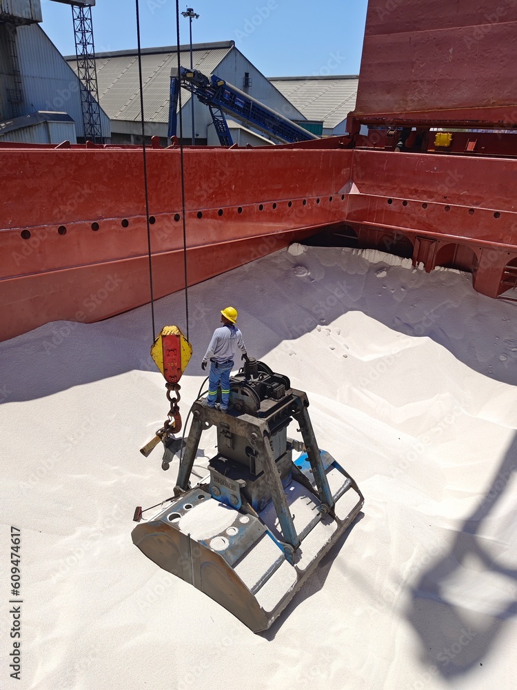 workers on a grab in the hold of cargo ship or a bulk carrier during ...