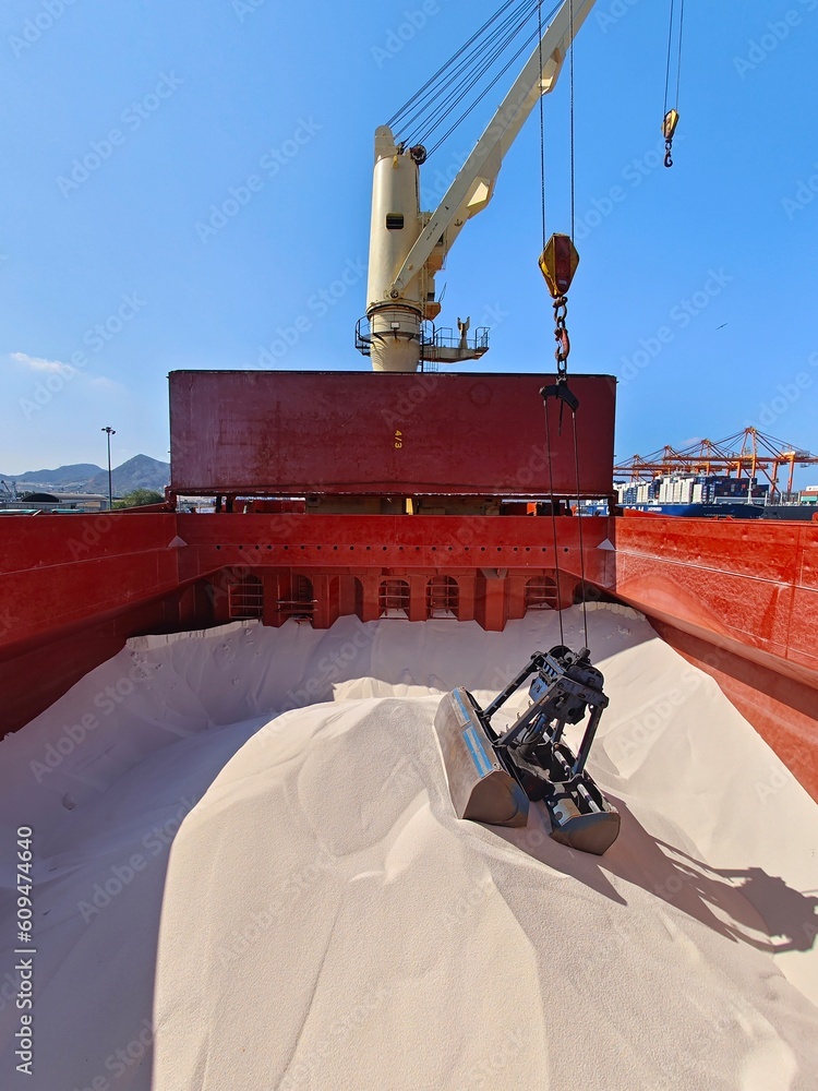A grab is grabbing cargo in the hold of cargo ship or a bulk carrier ...