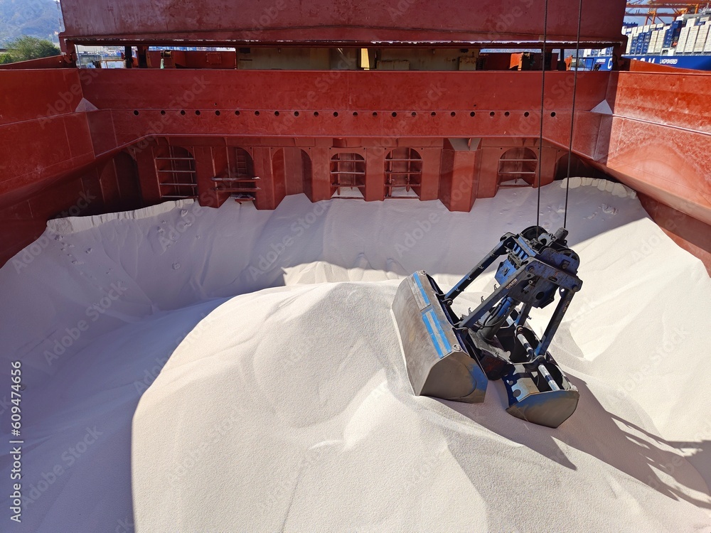 A grab is grabbing cargo in the hold of cargo ship or a bulk carrier ...