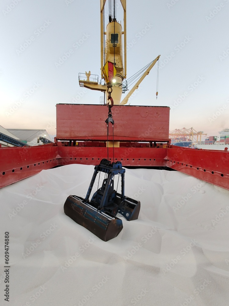 A grab is grabbing cargo in the hold of cargo ship or a bulk carrier ...