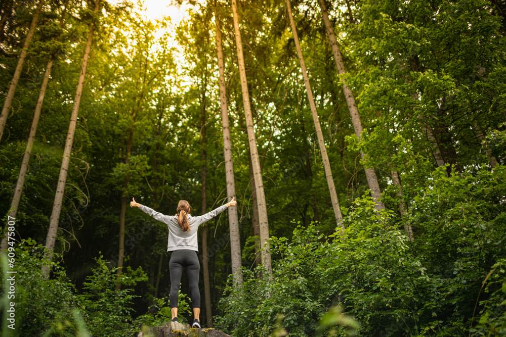 Woan standing in a pine forest looking up in awe enjoying feeling free ...