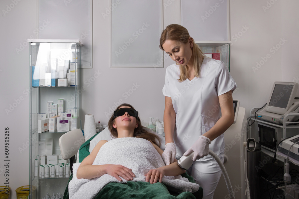 Laser hair removal on the hand.White gloves hold the epilation device ...