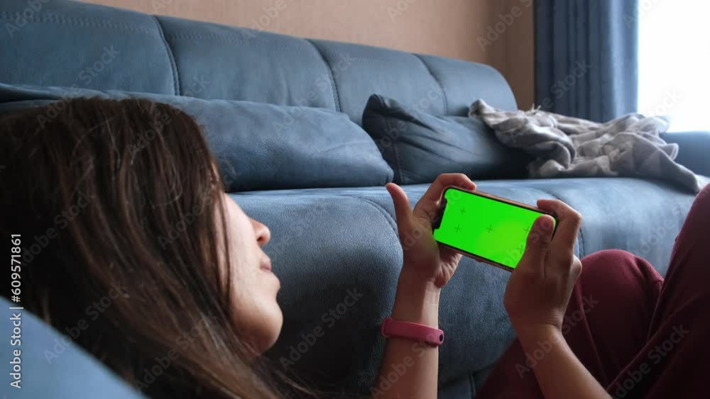 Girl playing mobile phone horizontally with green screen Back view ...