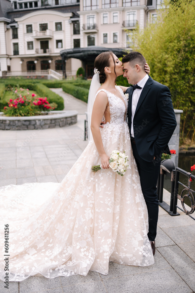 Beautiful bride and groom stand in front of luxury building. Newlyweds ...