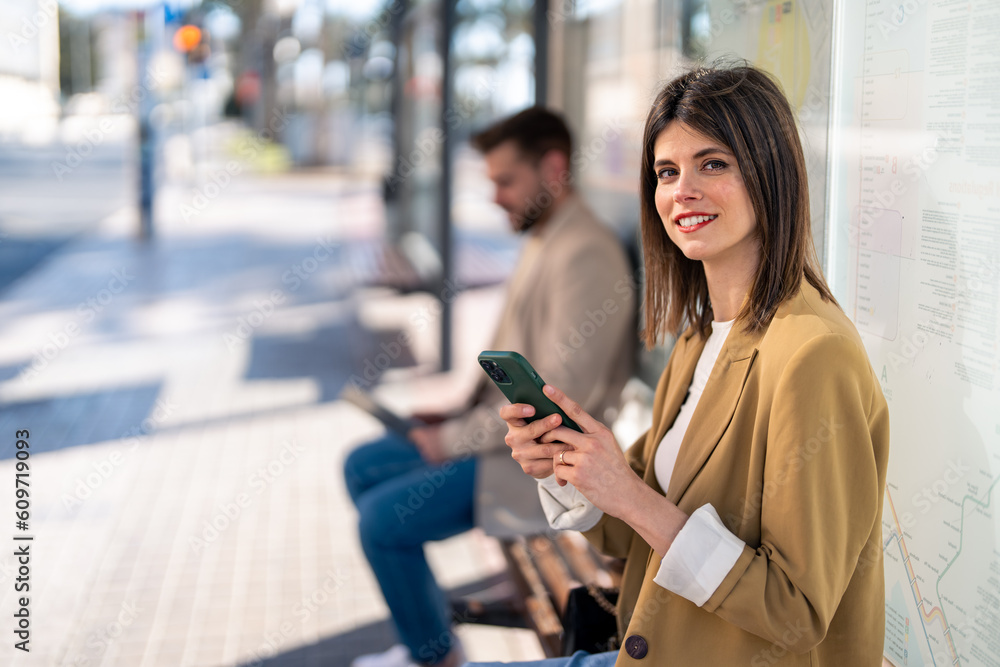 Confident young woman looking at camera holding mobile phone while ...