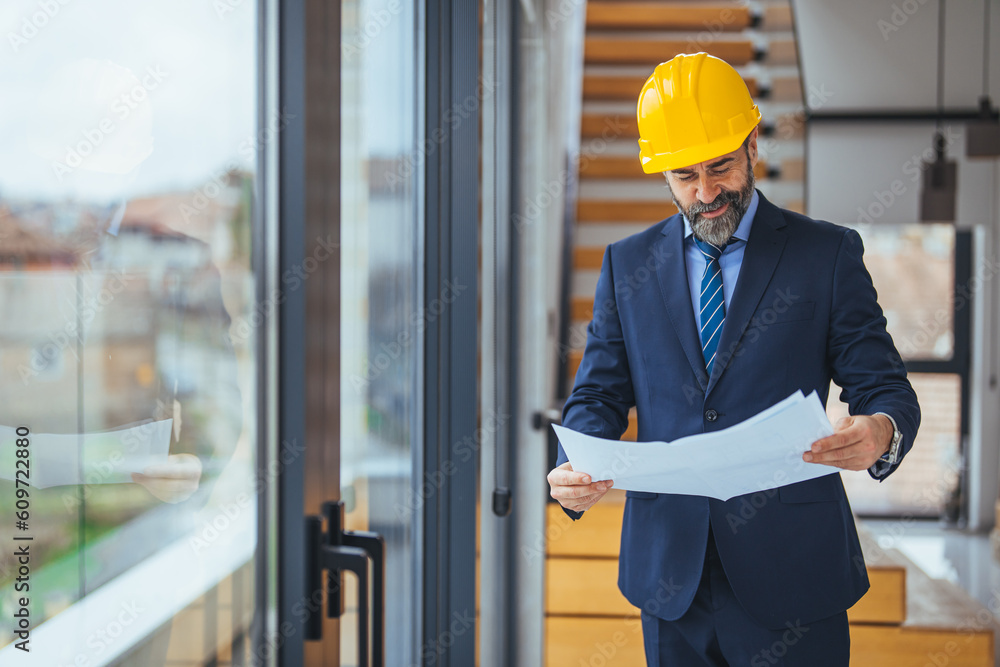 Portrait of an engineer holding a blueprint at a construction site ...