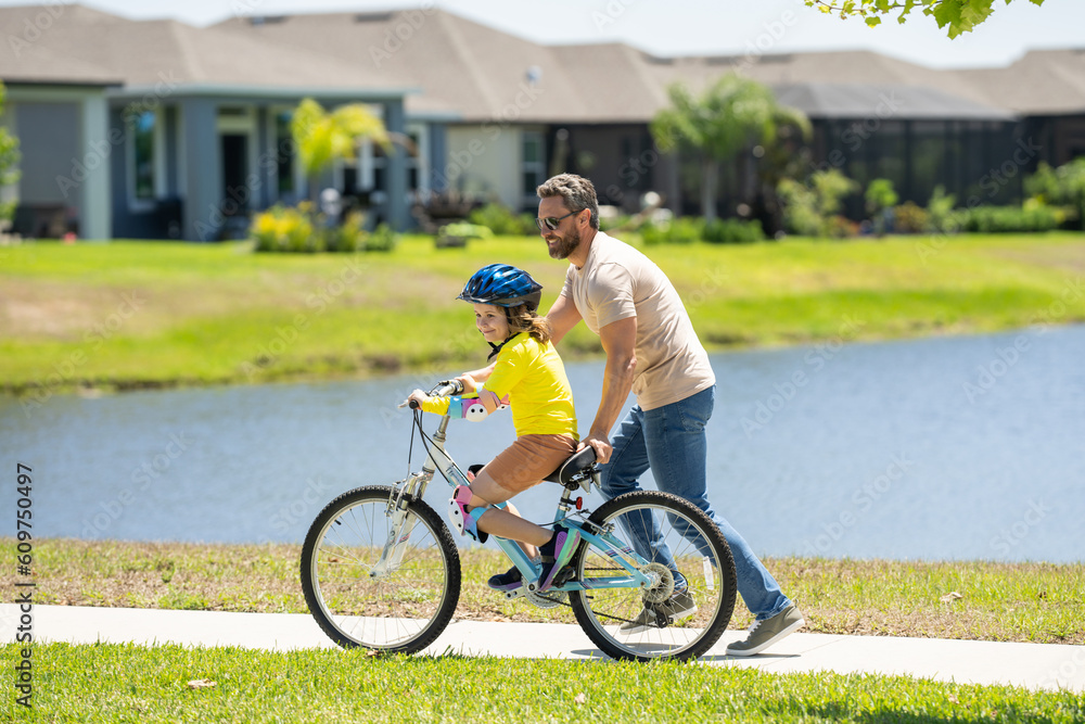 Father teaching son riding bike. Father helping excited son to ride a ...