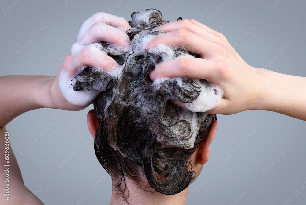 Hair washing procedure. A young girl washing her hair with a shampoo on ...